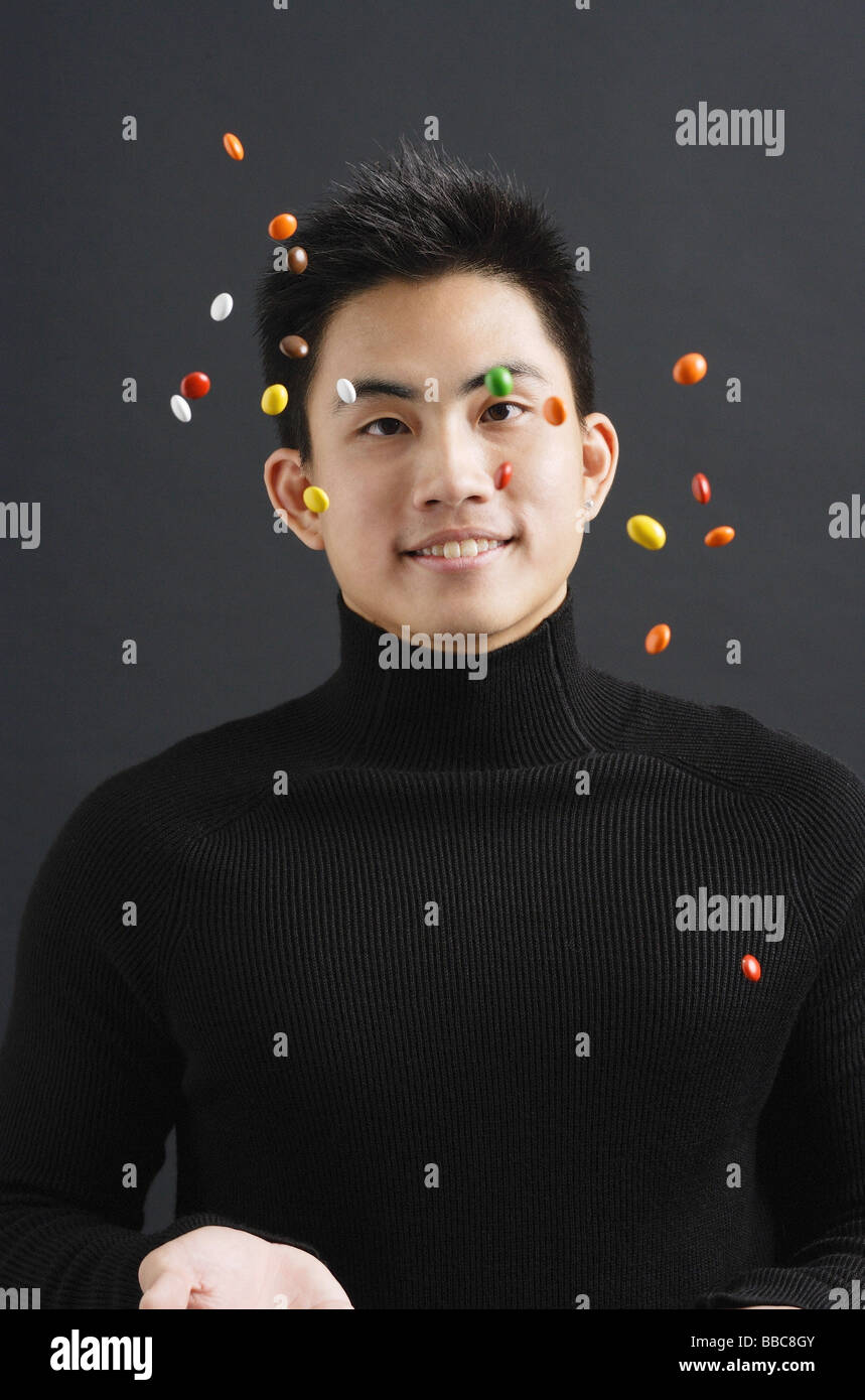 Young man dressed in black throwing multi coloured candy in the air ...
