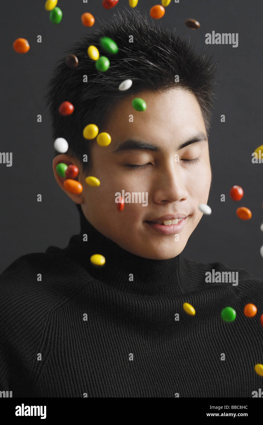 Young man dressed in black, multi coloured candy in the air around him ...