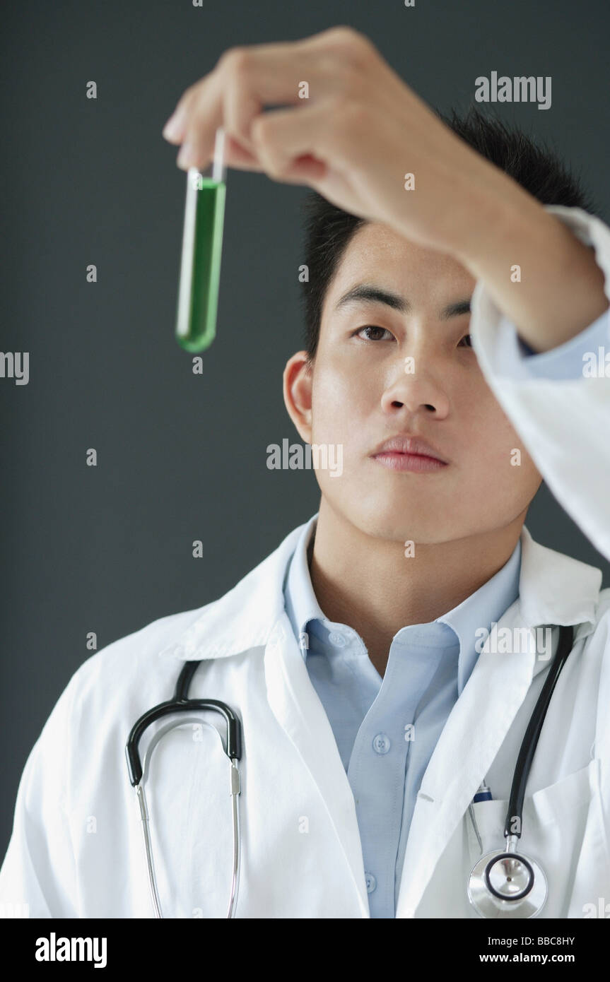 Doctor looking at test tube filled with green liquid Stock Photo - Alamy
