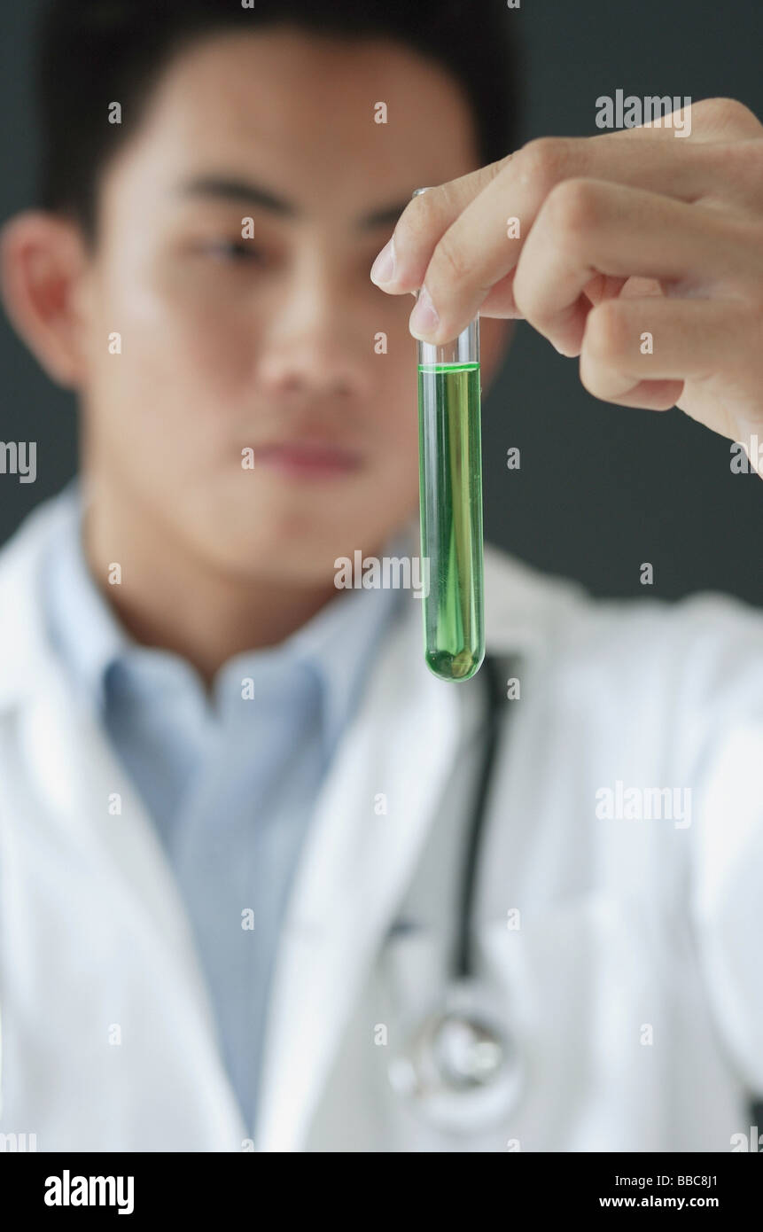 Doctor looking at test tube filled with green liquid Stock Photo - Alamy