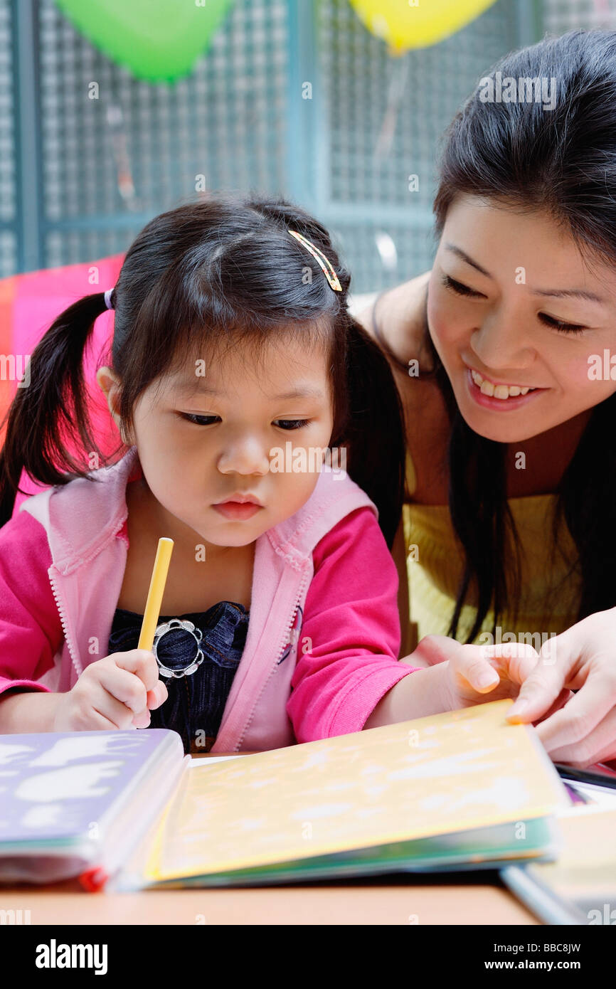 Mother with young daughter, looking through book Stock Photo - Alamy