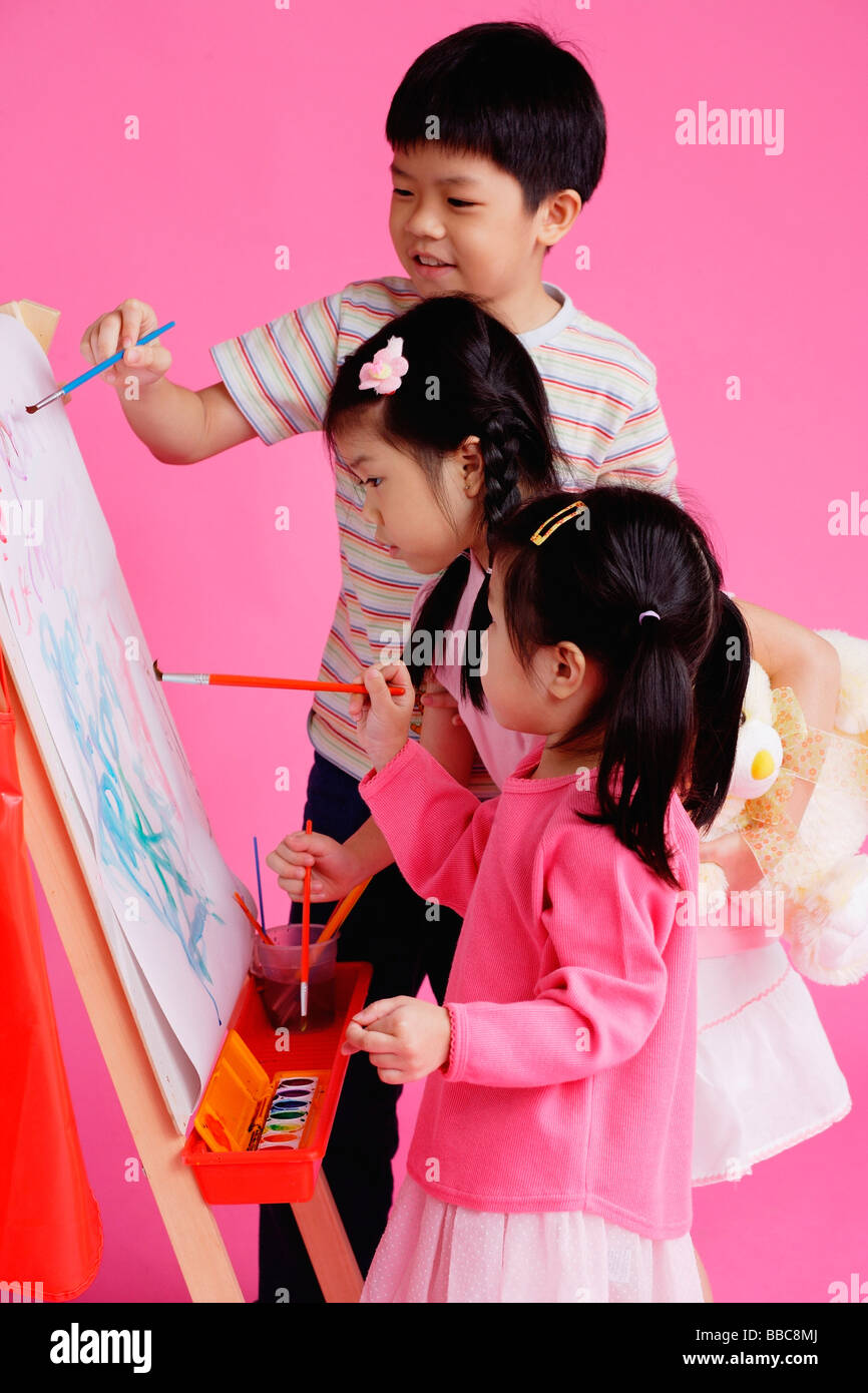 Three children painting on easel Stock Photo - Alamy