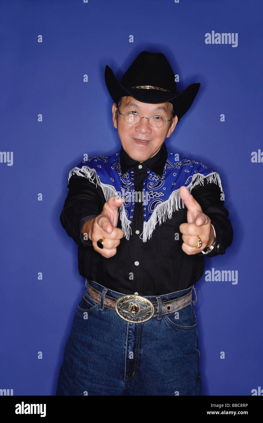 Senior man dressed in cowboy attire, pointing fingers at camera Stock ...