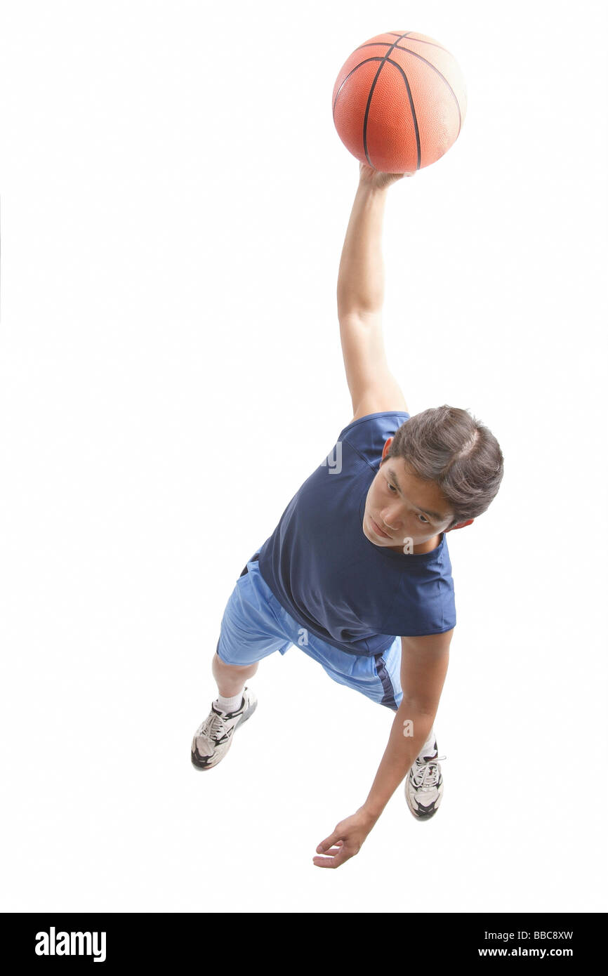 Young man holding basketball in one hand, jumping Stock Photo - Alamy