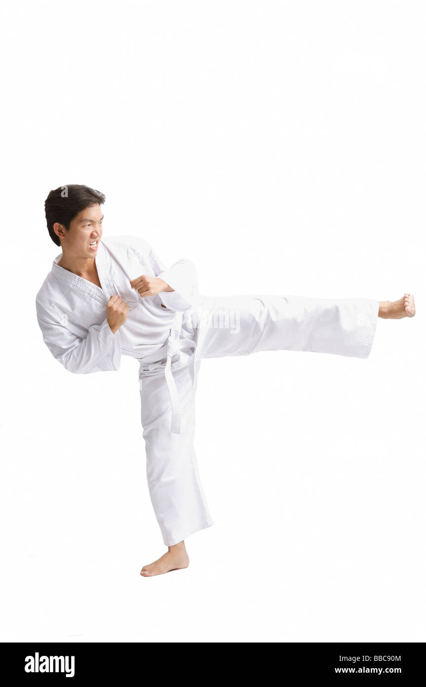 Young man wearing martial arts uniform, standing on one leg Stock Photo ...