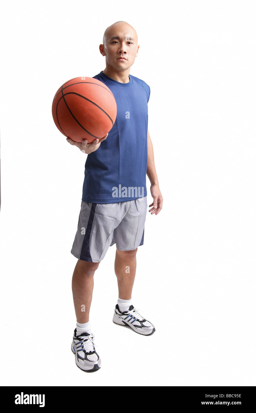 Young man standing, holding basketball Stock Photo - Alamy