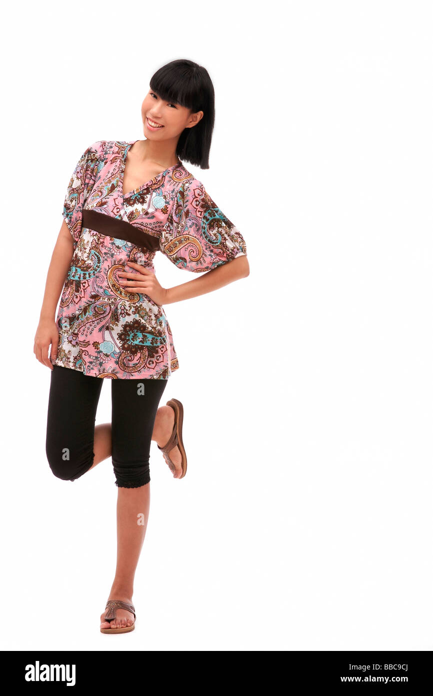 Young woman with hand on hip, standing on one leg Stock Photo - Alamy