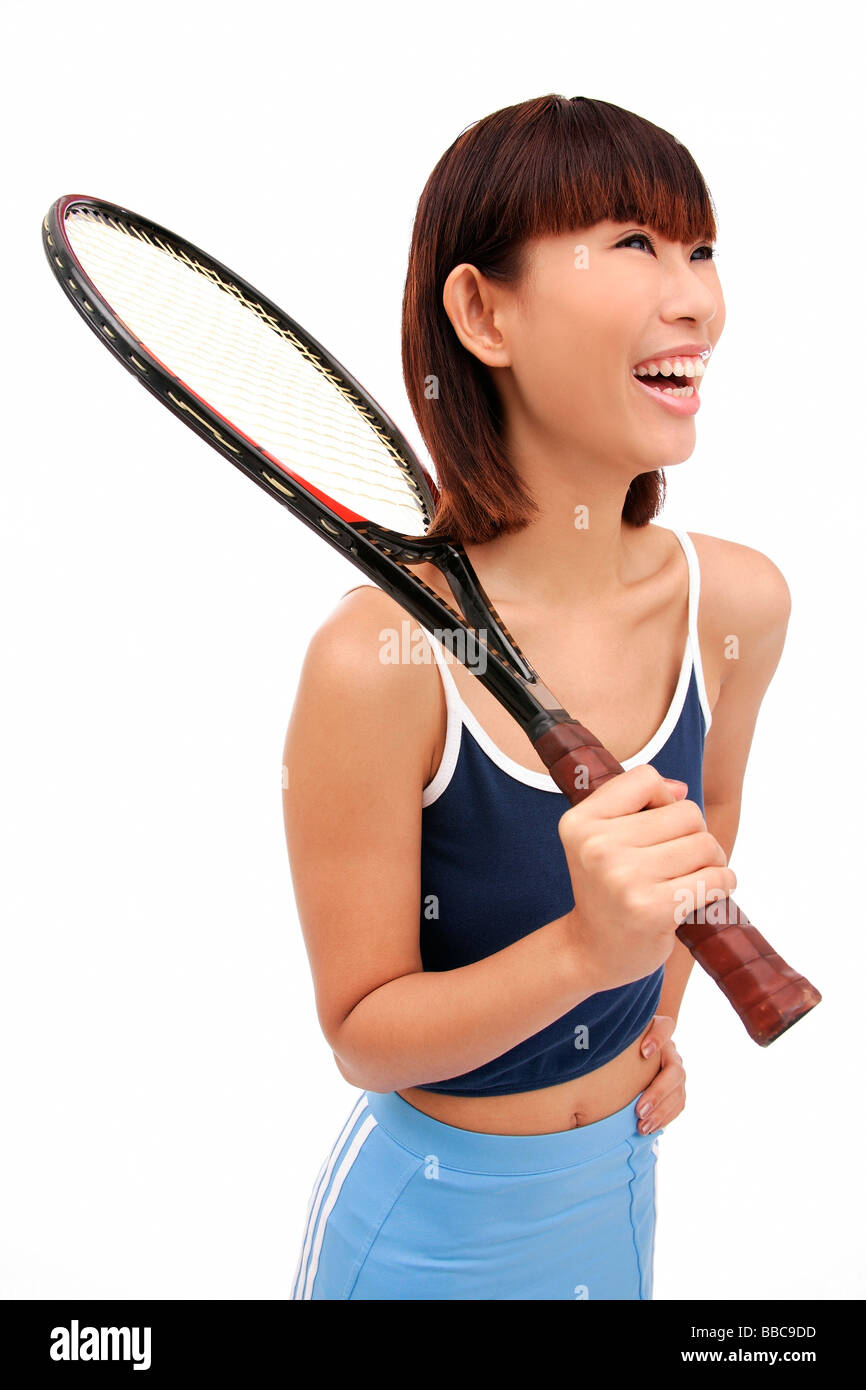 Young woman holding tennis racket over shoulder, smiling Stock Photo ...