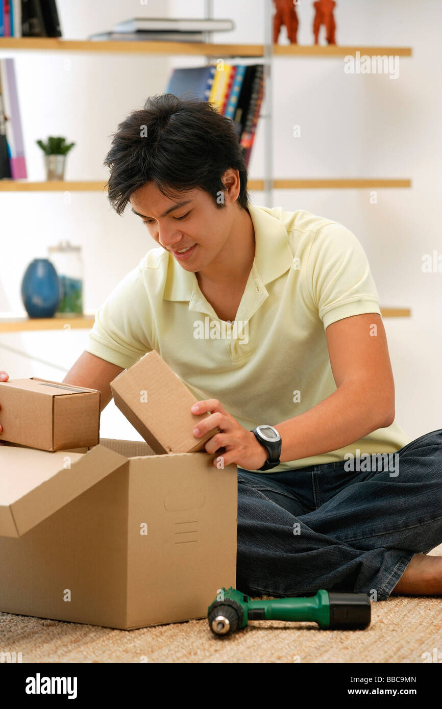 Man sitting on floor, looking through box Stock Photo - Alamy