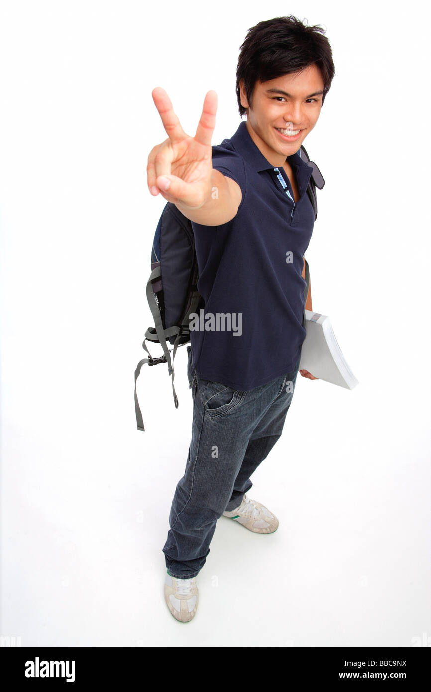 Young man carrying books and a backpack, making peace sign Stock Photo ...