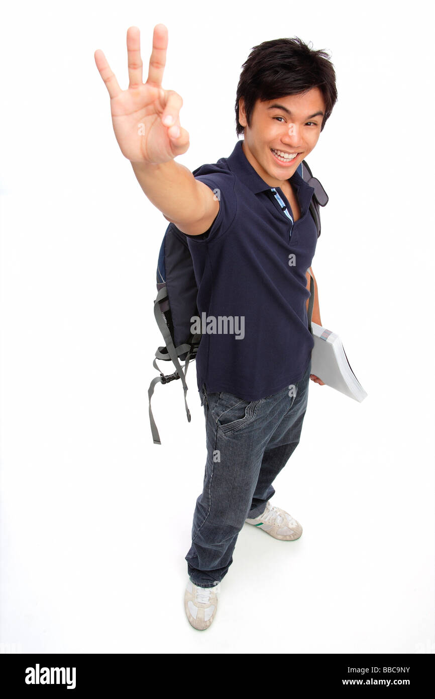 Young man with books and a backpack, making hand sign Stock Photo - Alamy