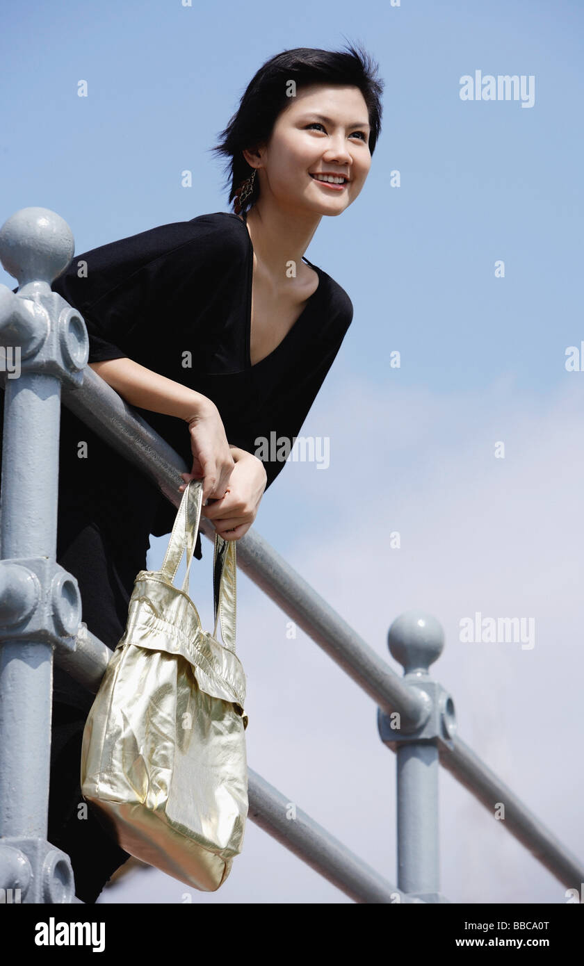Woman leaning on railing, smiling, looking away Stock Photo - Alamy