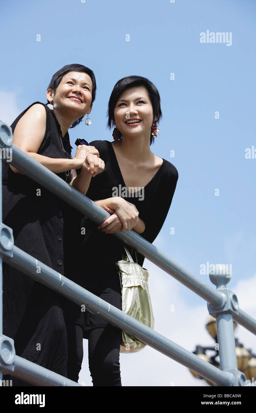 Women leaning on railing, smiling, looking away Stock Photo - Alamy