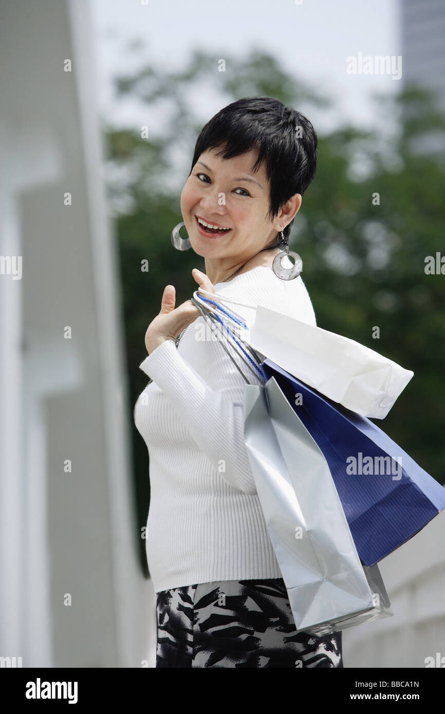 Mature woman carrying shopping bags, looking over shoulder Stock Photo ...