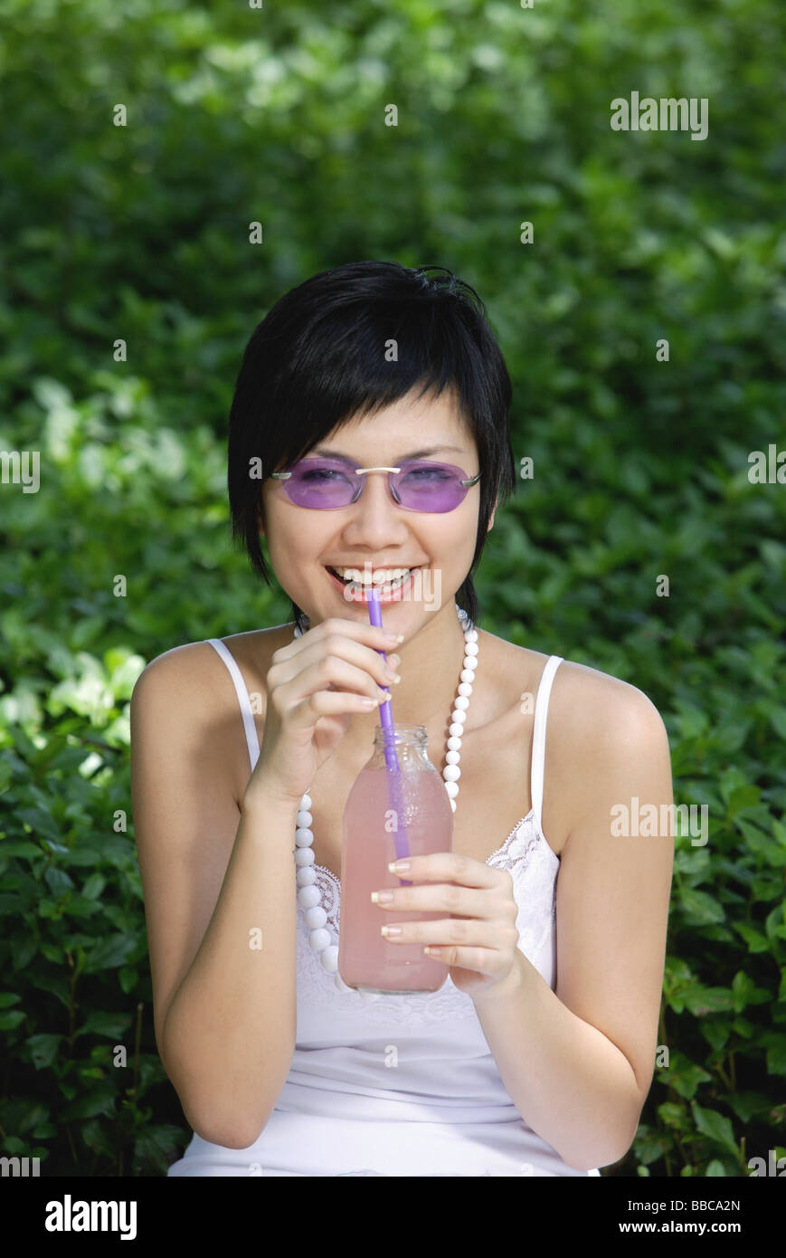 Woman drinking from a straw, smiling at camera Stock Photo - Alamy