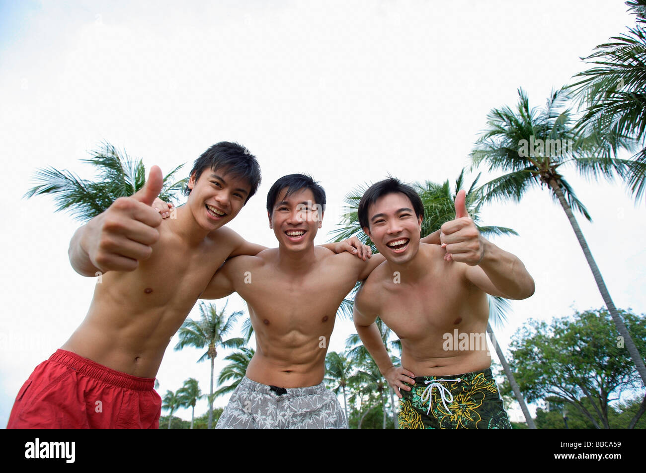 Three men with arms around each other, smiling at camera Stock Photo ...