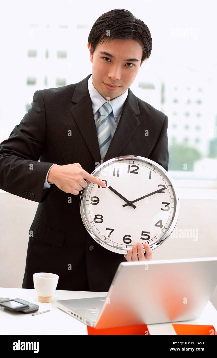 Businessman holding and pointing at clock Stock Photo - Alamy