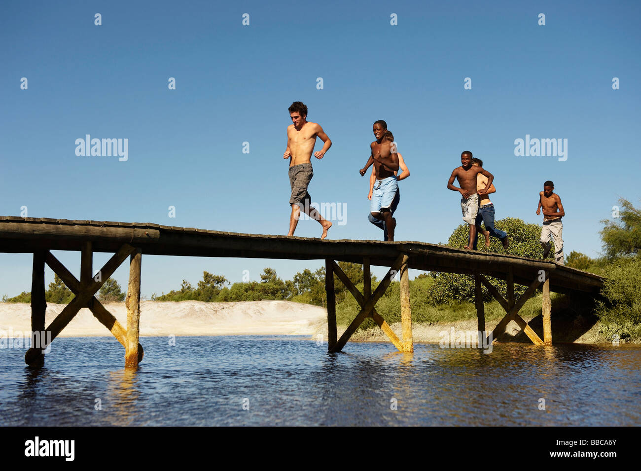 Group of teenagers running across jetty Stock Photo - Alamy