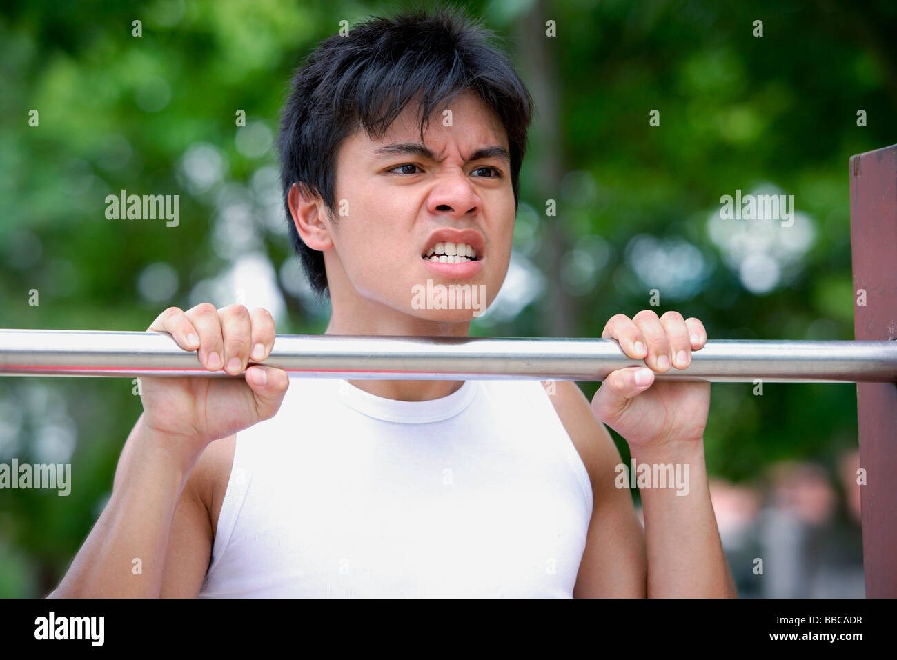 Young man doing chin-ups, clenching teeth Stock Photo - Alamy