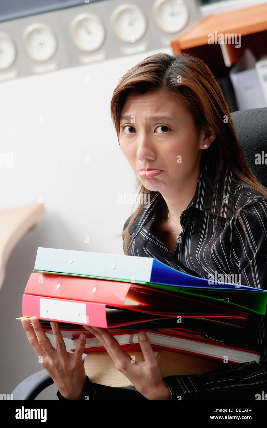 Female executive carrying folders and binders, frowning Stock Photo - Alamy