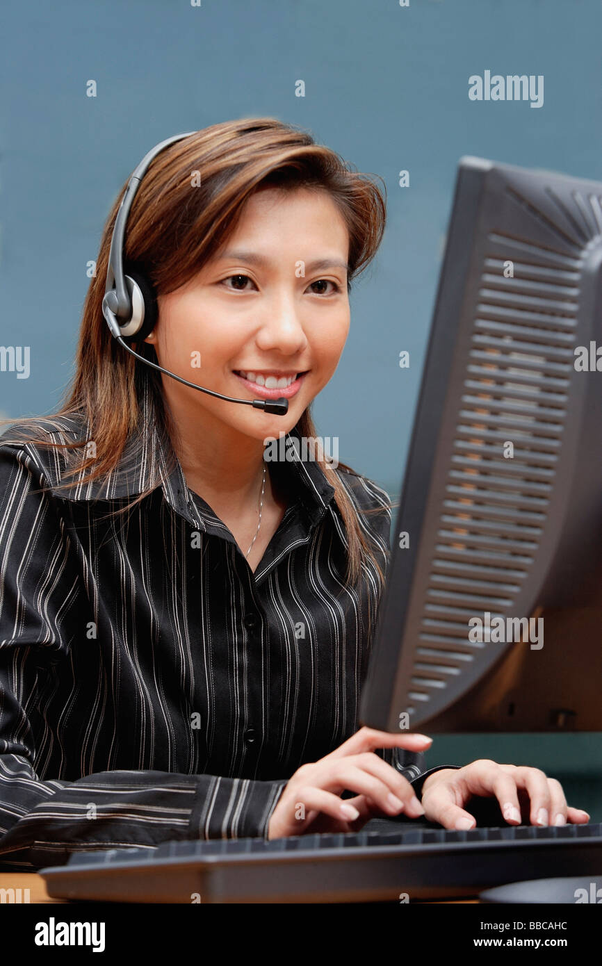 Female executive with hands free device, using computer Stock Photo - Alamy