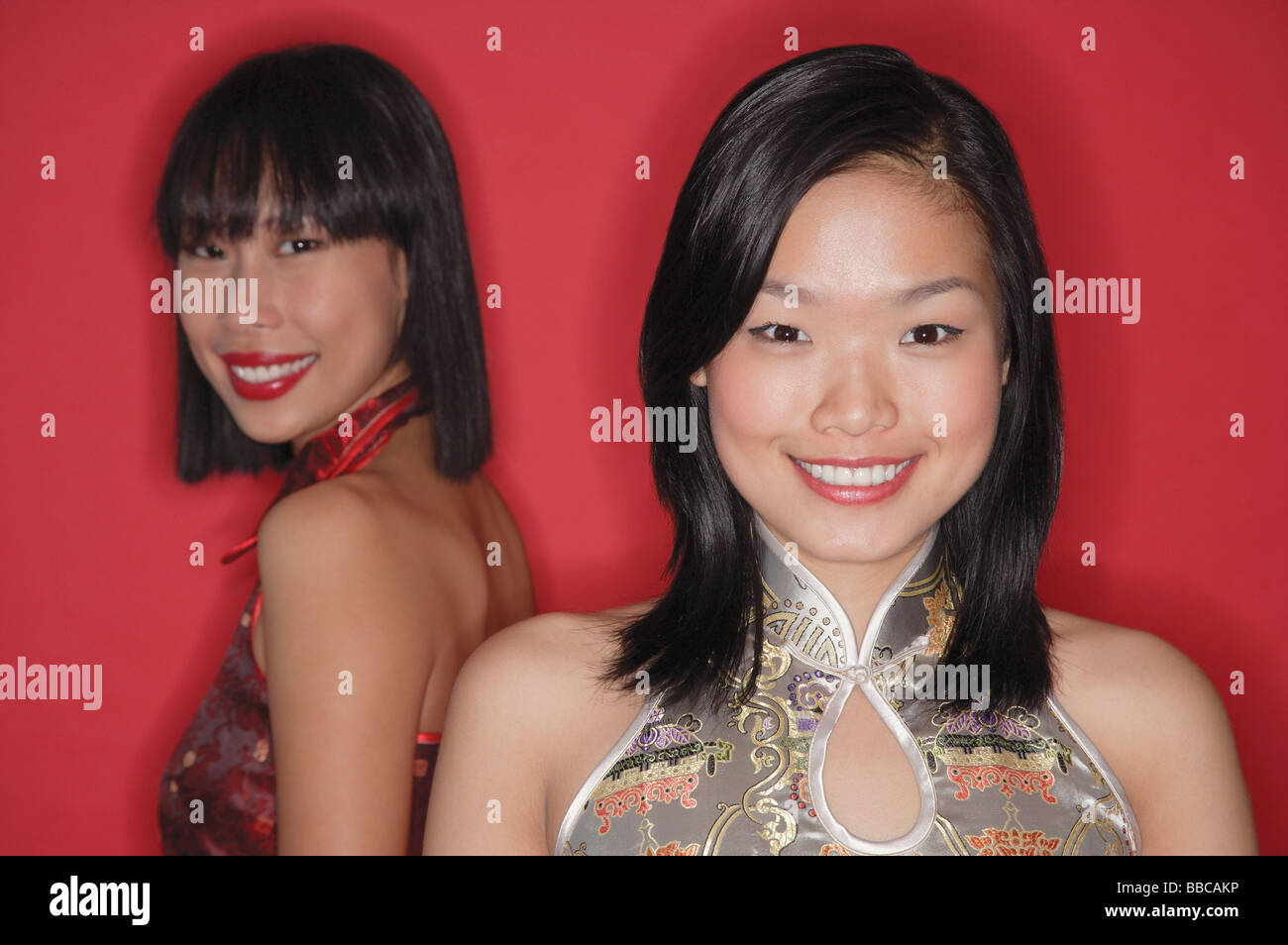 Two women, red background, smiling at camera Stock Photo - Alamy