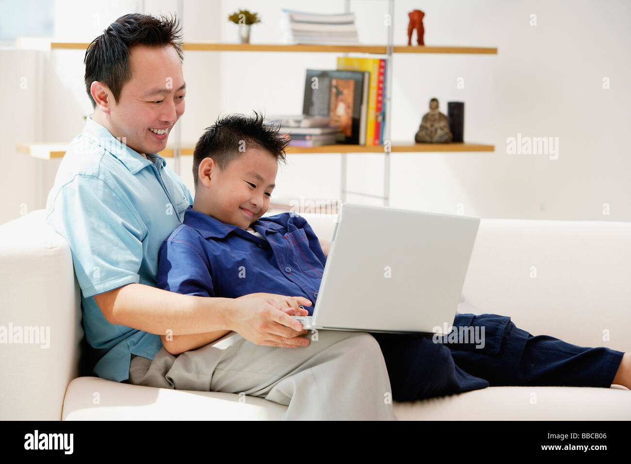 Father and son in living room, looking at laptop Stock Photo - Alamy