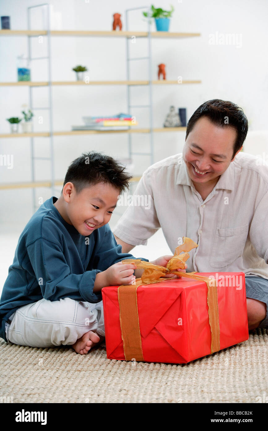 Boy opening gift box, father next to him Stock Photo - Alamy