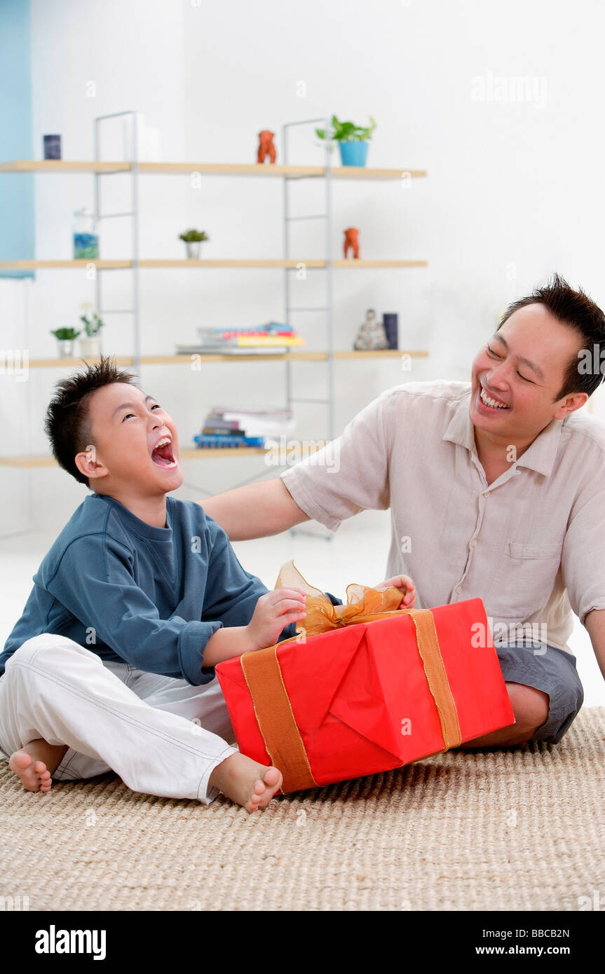 Father and son at home, boy opening gift, looking up Stock Photo - Alamy