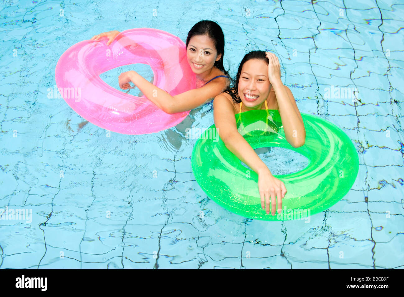Women in swimming pool, holding inflatable ring, looking at camera ...