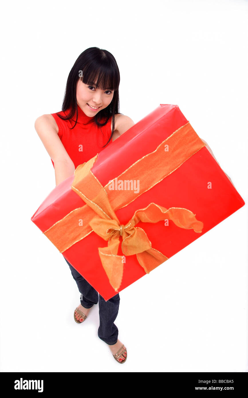 Young woman holding big red gift box towards camera Stock Photo - Alamy