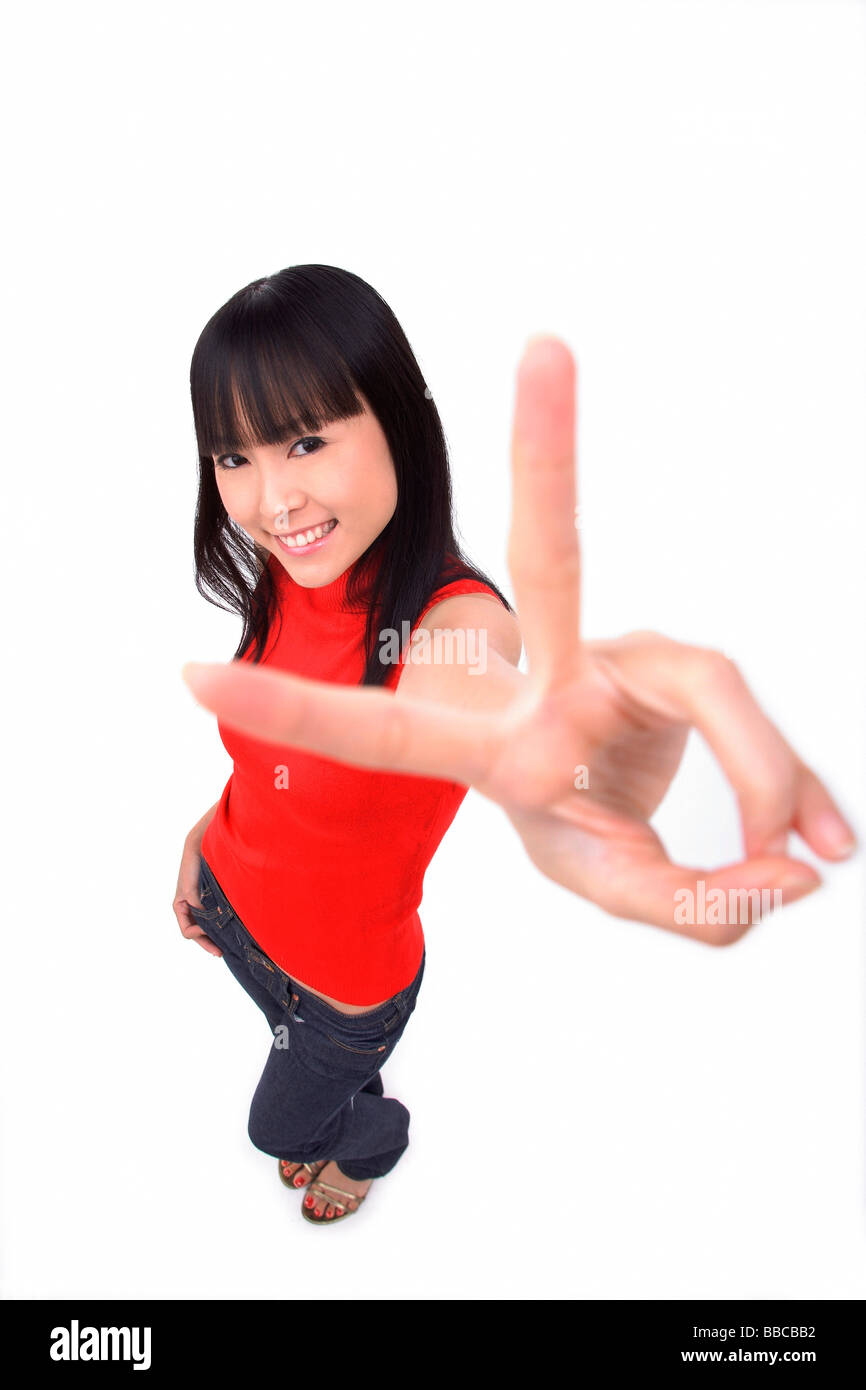 Young woman making peace sign at camera Stock Photo - Alamy