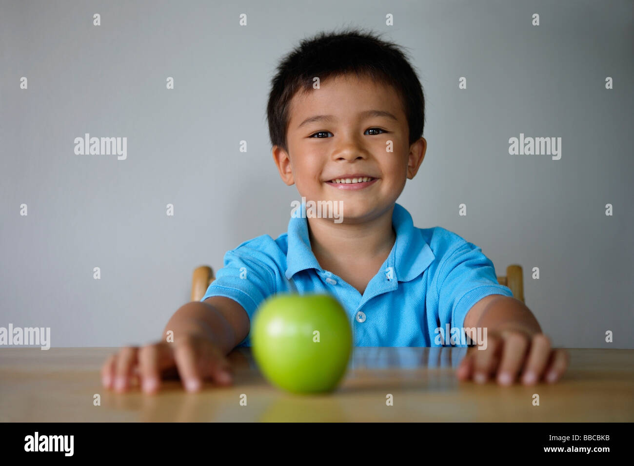 Boy sitting at table with green apple Stock Photo - Alamy
