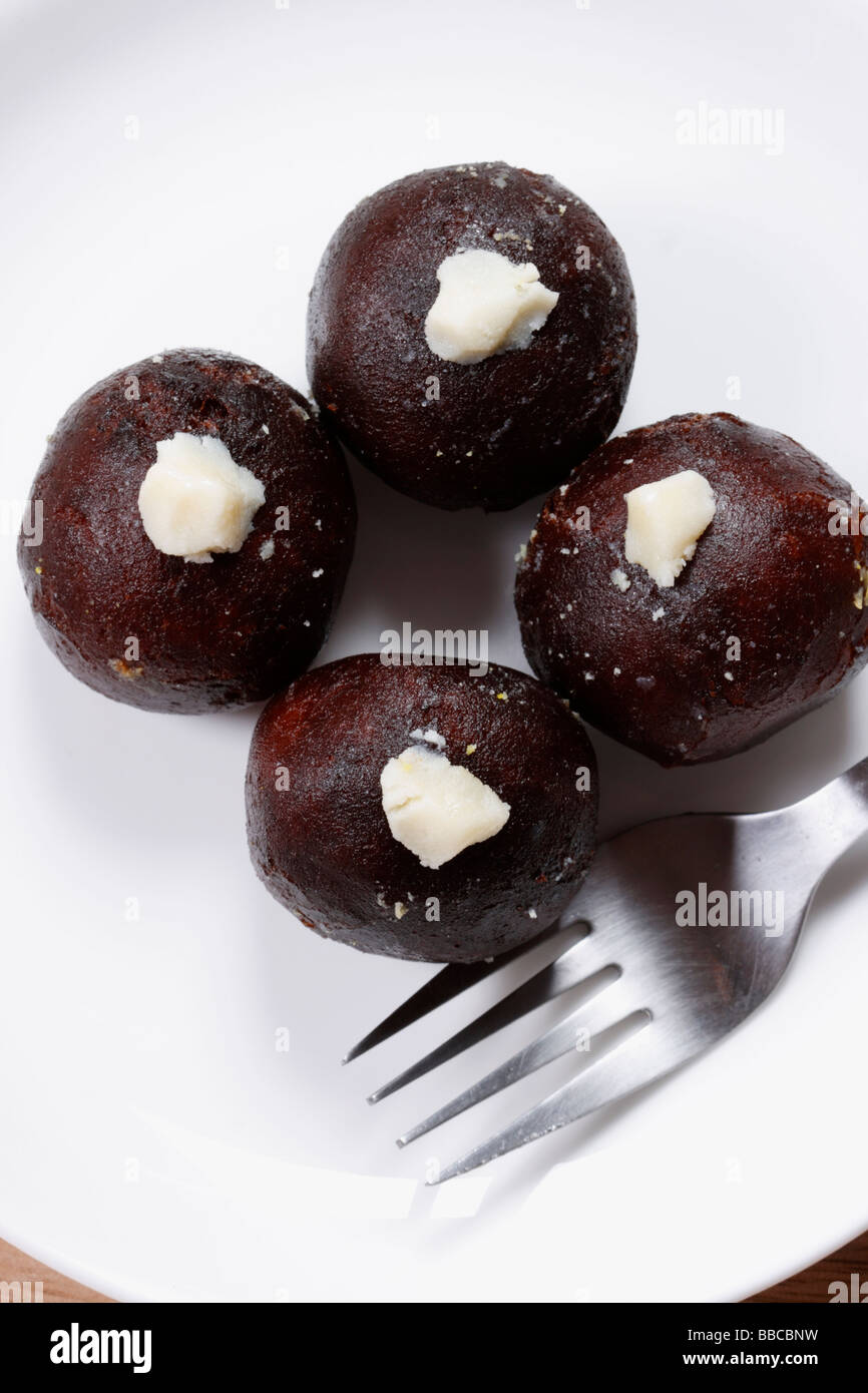 Dark brown gulab jamuns coated with desiccated coconut Stock Photo - Alamy
