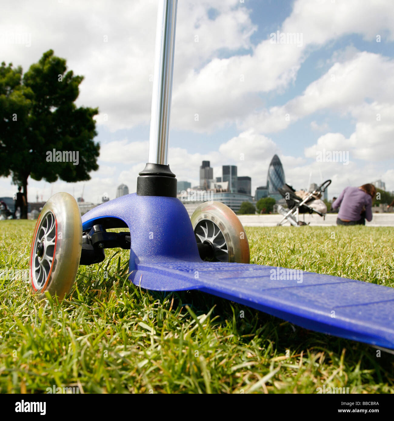 childs scooter in an inner city london park with the city of london in ...