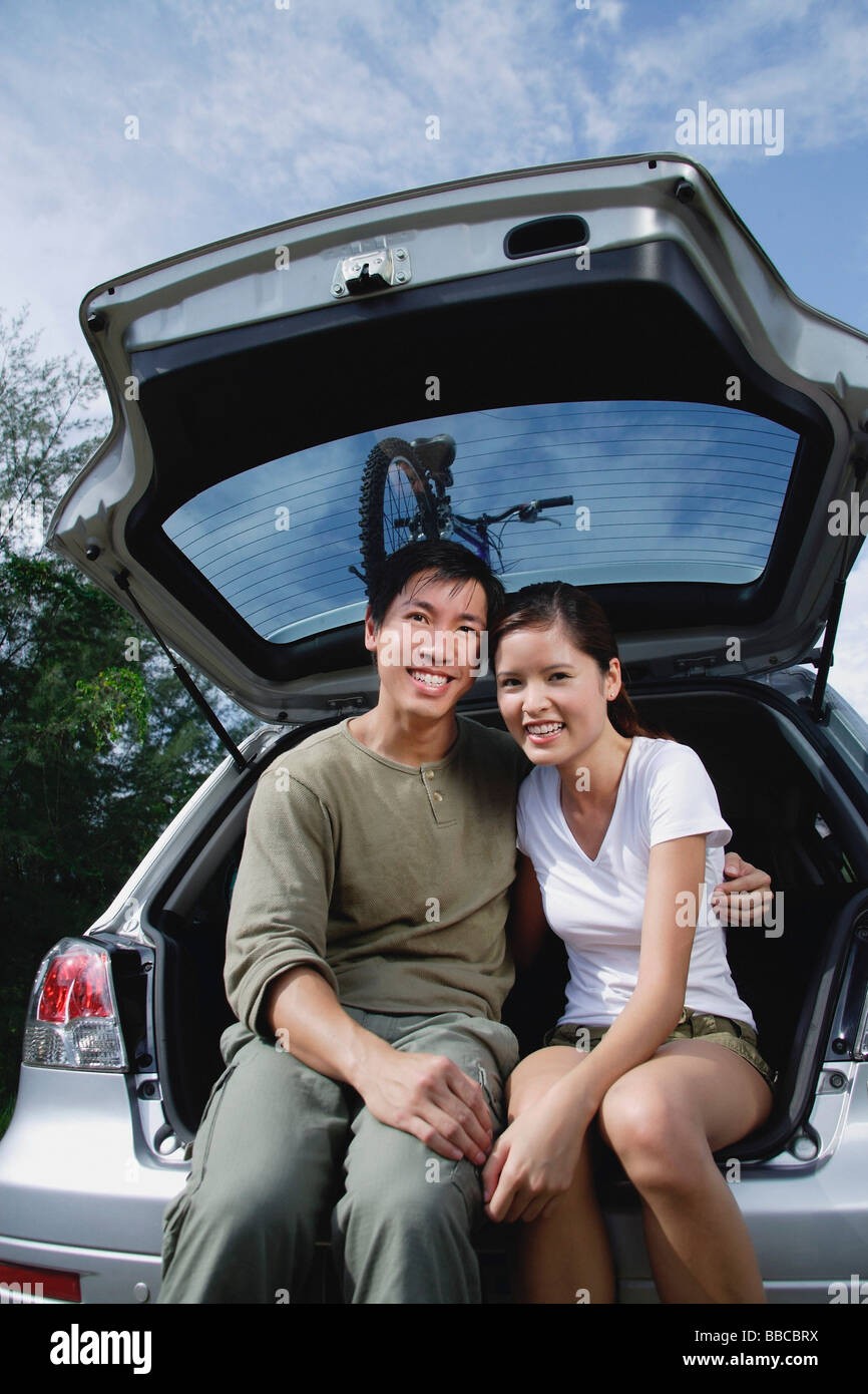 Couple sitting in boot of car, smiling at camera Stock Photo - Alamy
