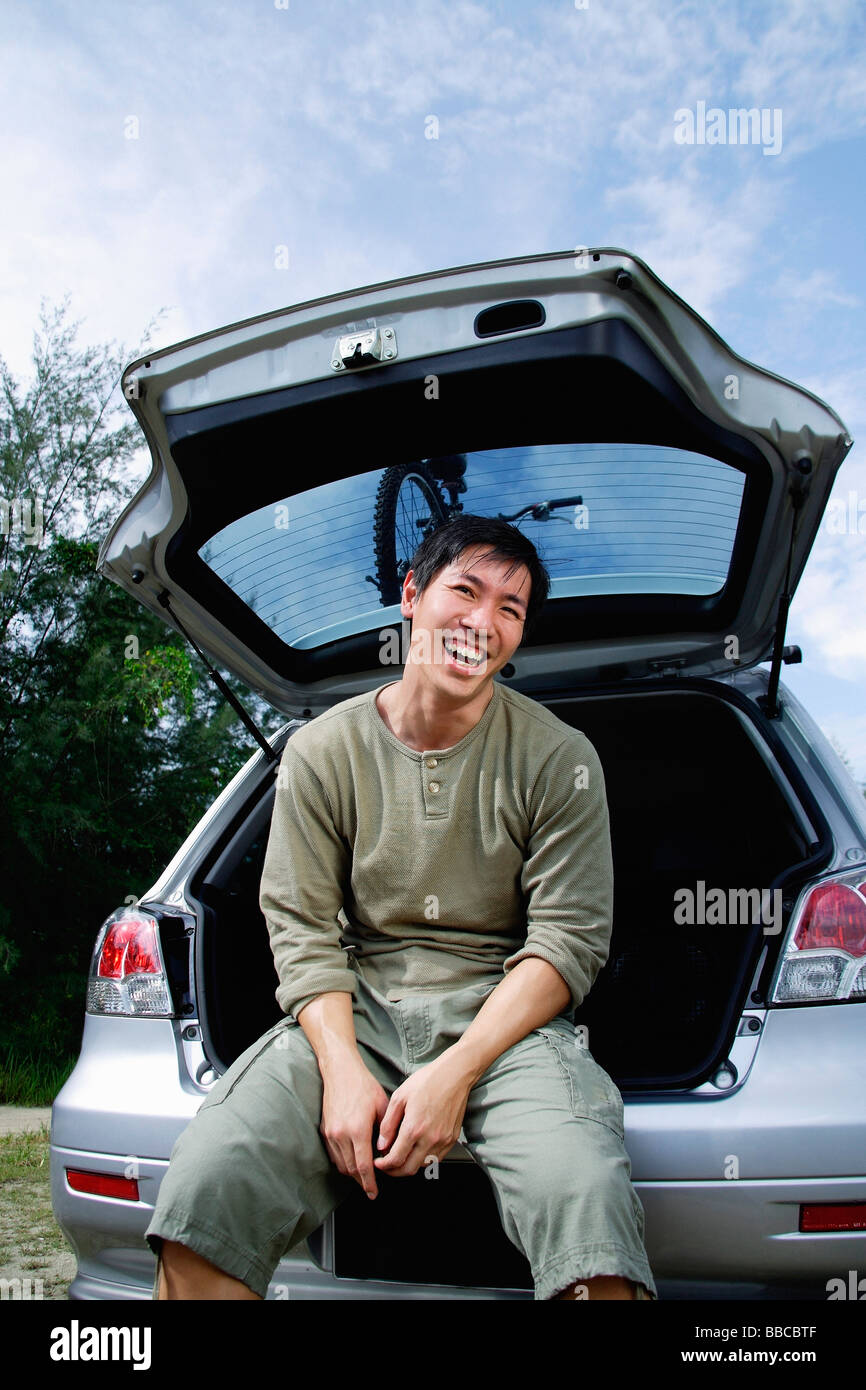 Man sitting in boot of car Stock Photo - Alamy