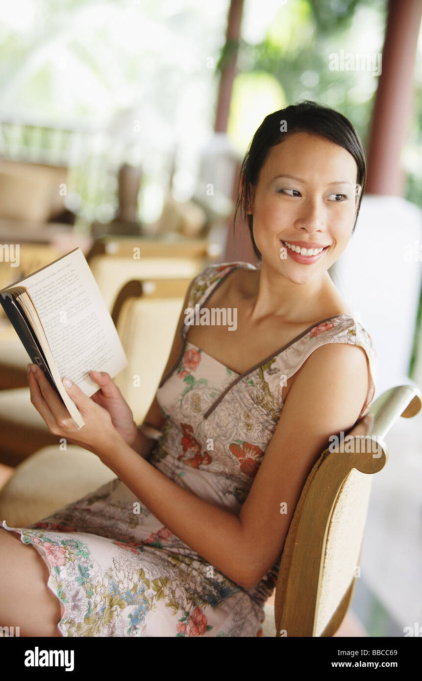 Woman sitting, holding a book, looking over shoulder Stock Photo - Alamy