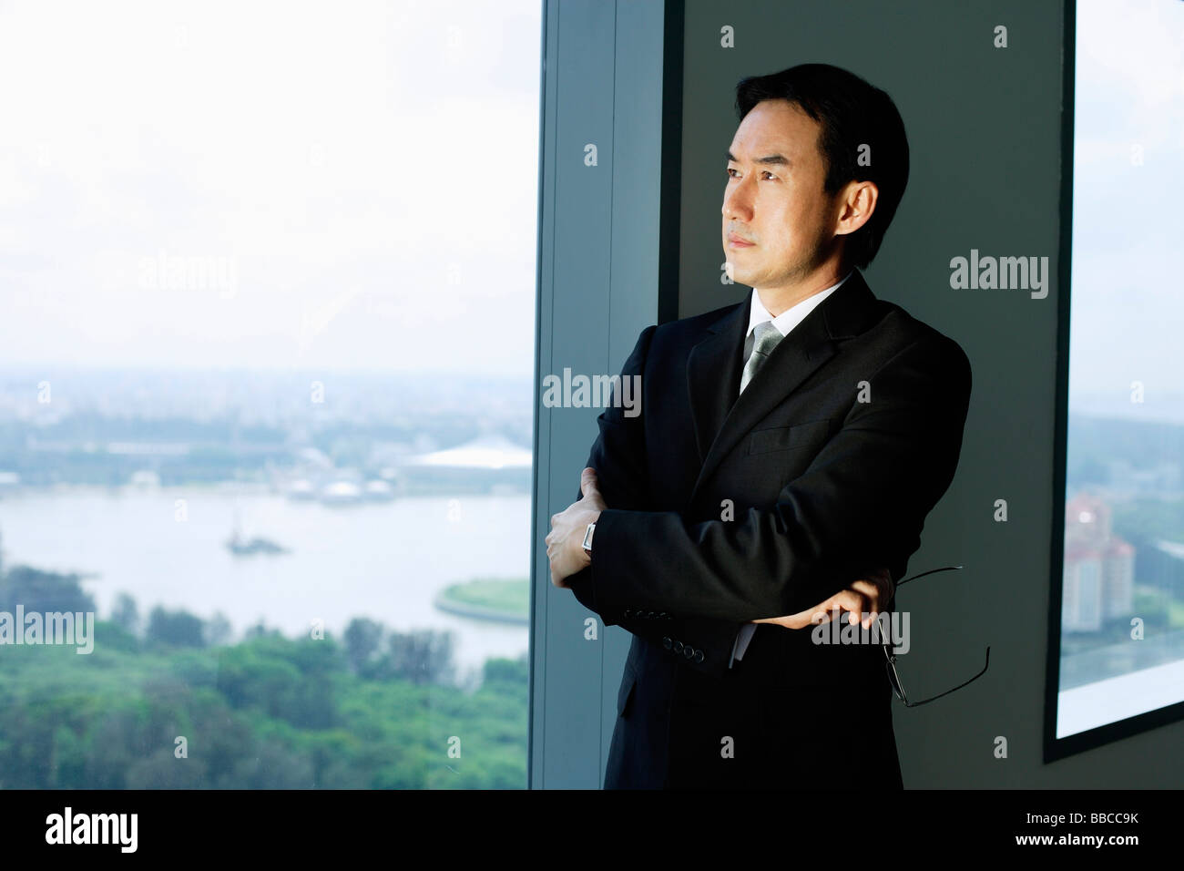 Businessman standing next to window, looking out Stock Photo - Alamy