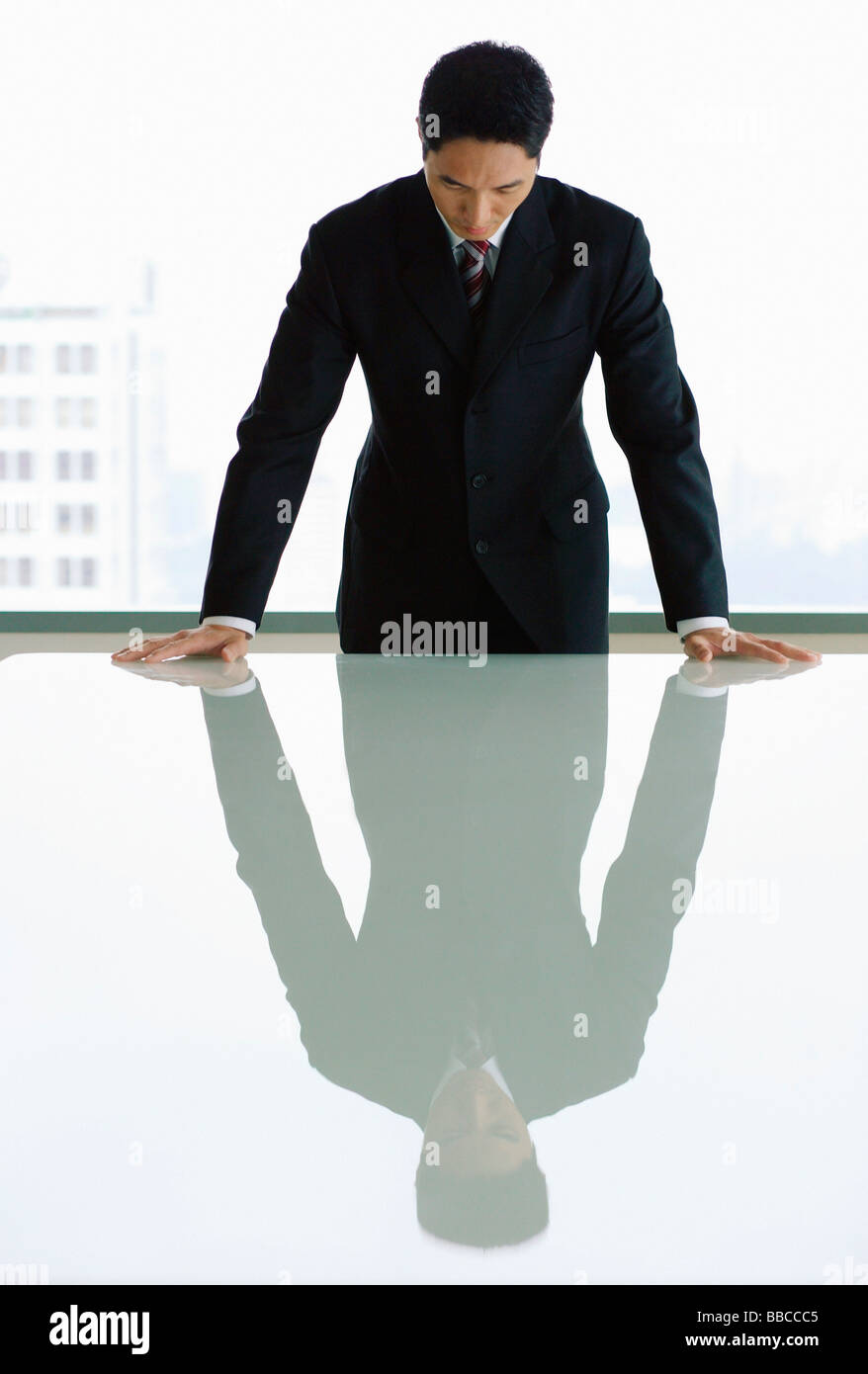 Businessman standing with hands on table, looking down Stock Photo - Alamy