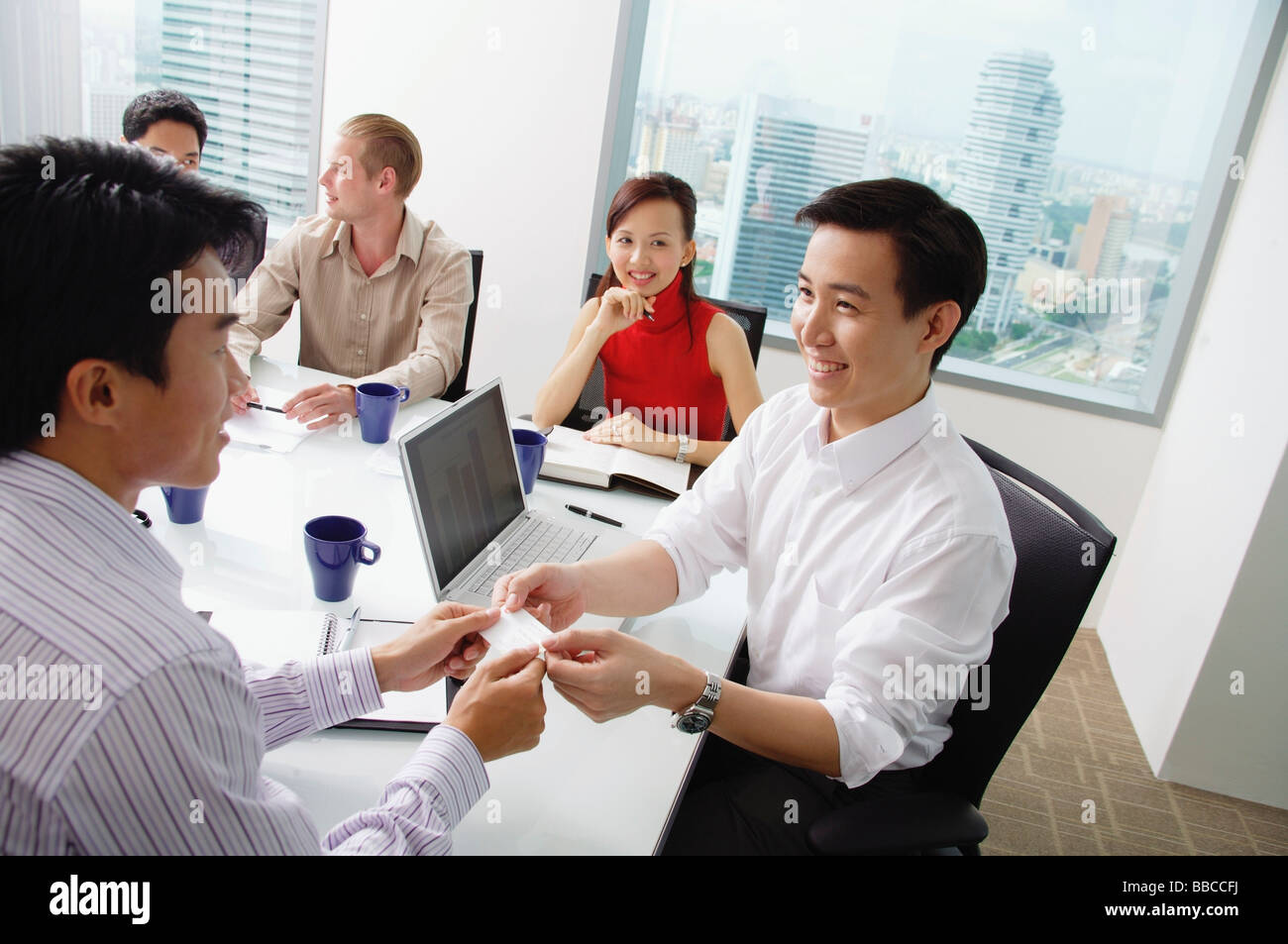 Executives around conference table, two businessmen exchanging business ...