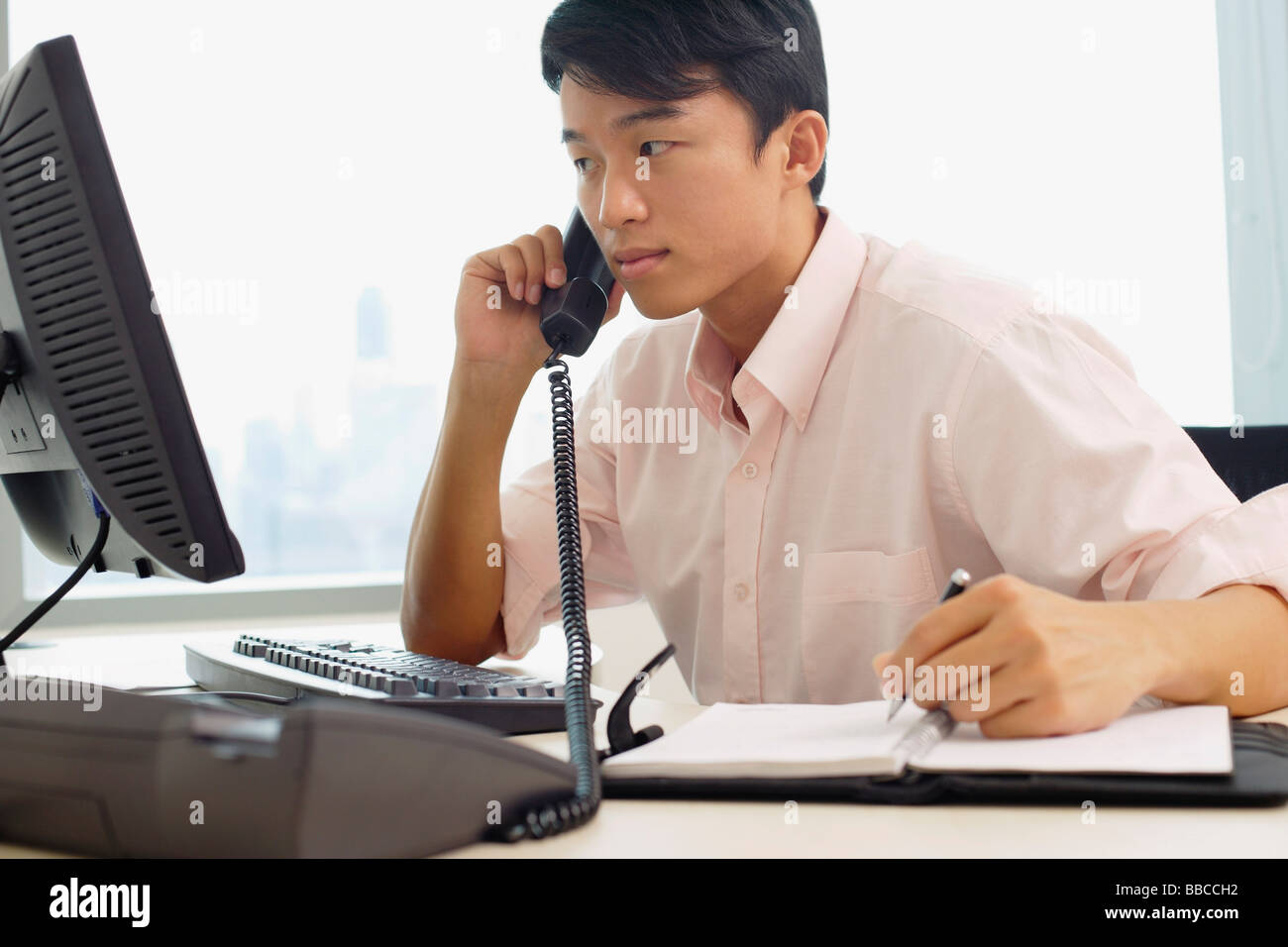 Male executive sitting at office desk, using telephone Stock Photo - Alamy