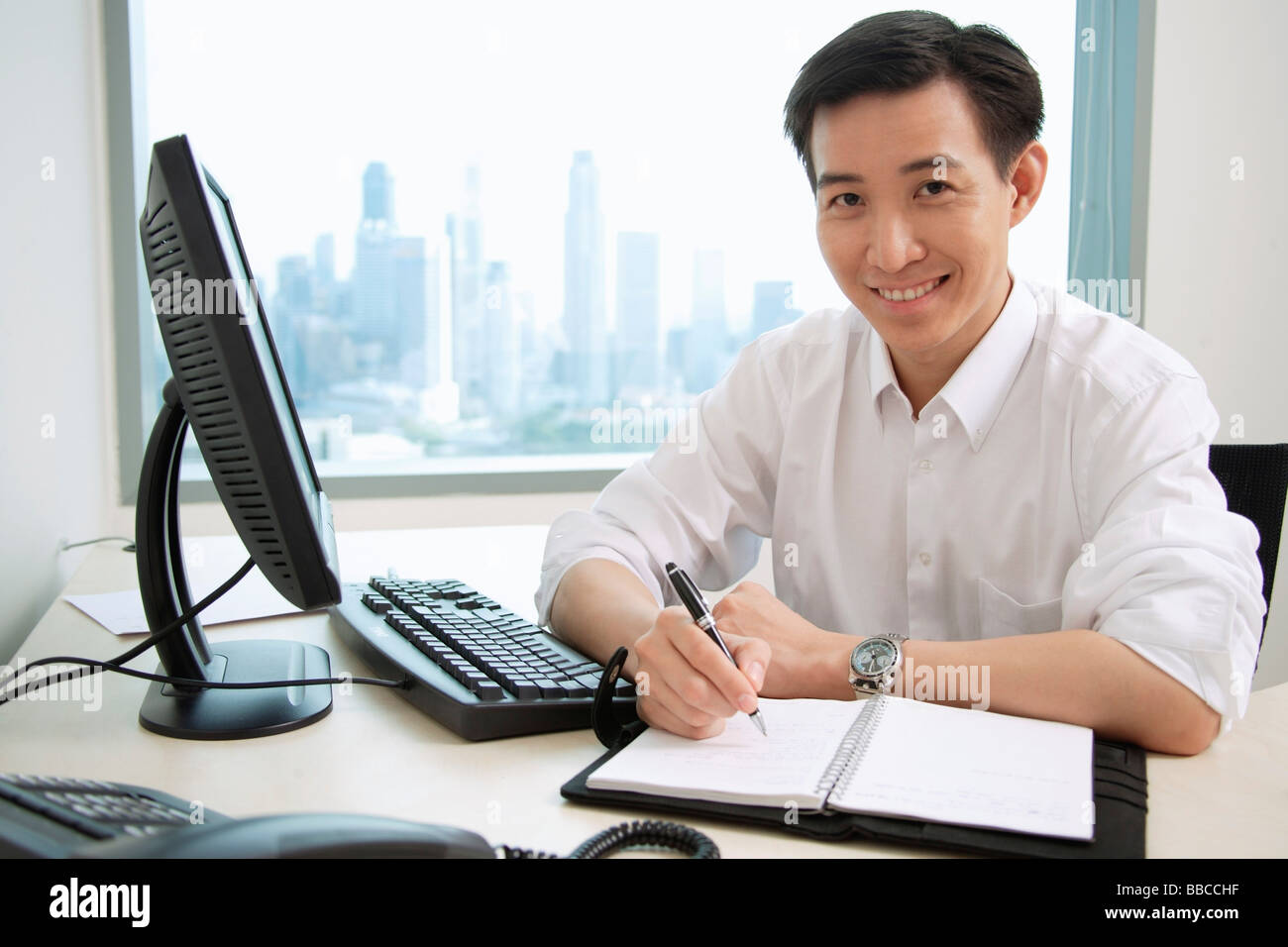 Male executive sitting at office desk, looking at camera, smiling Stock ...