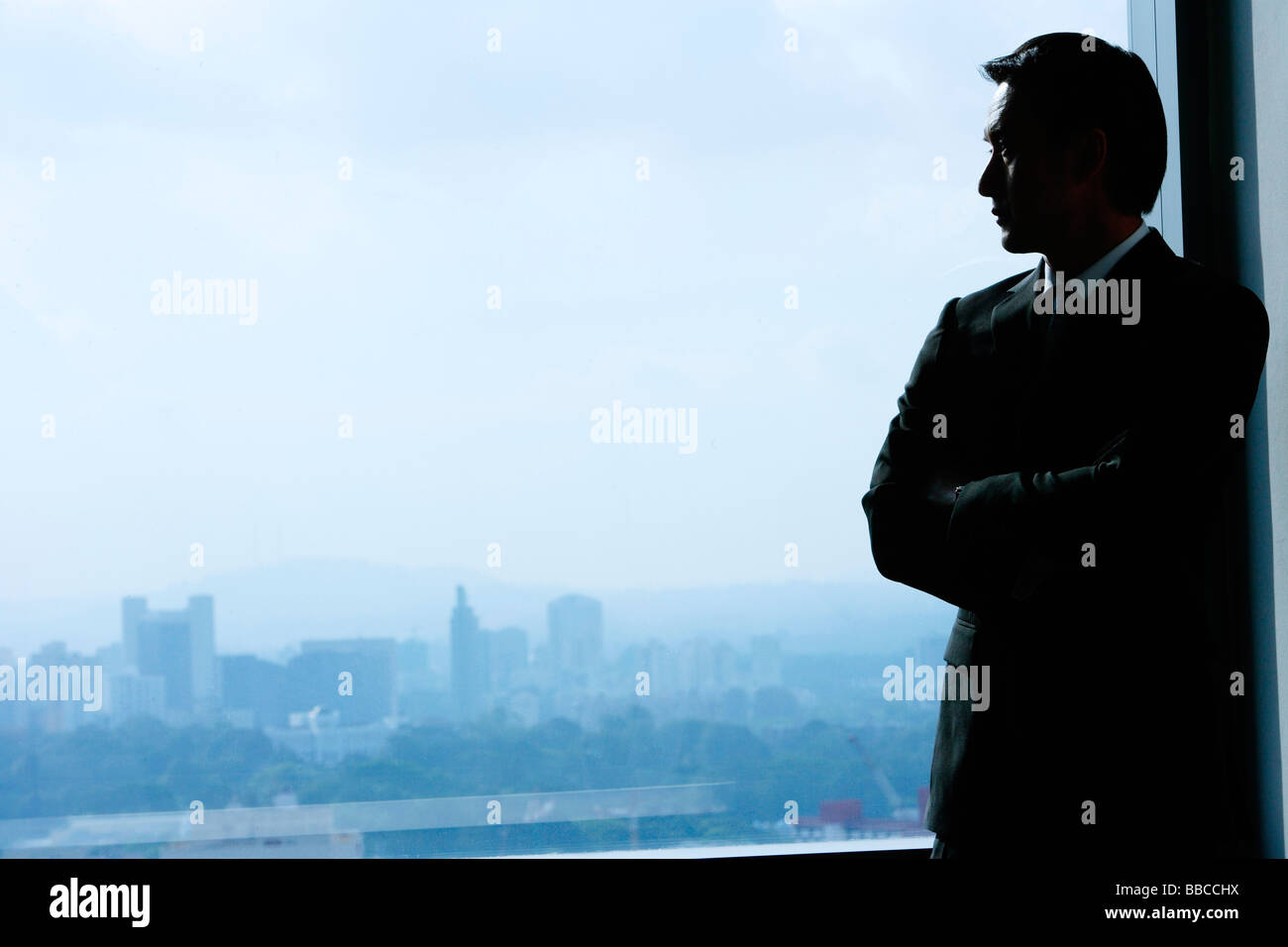 Businessman standing next to window, looking out Stock Photo - Alamy