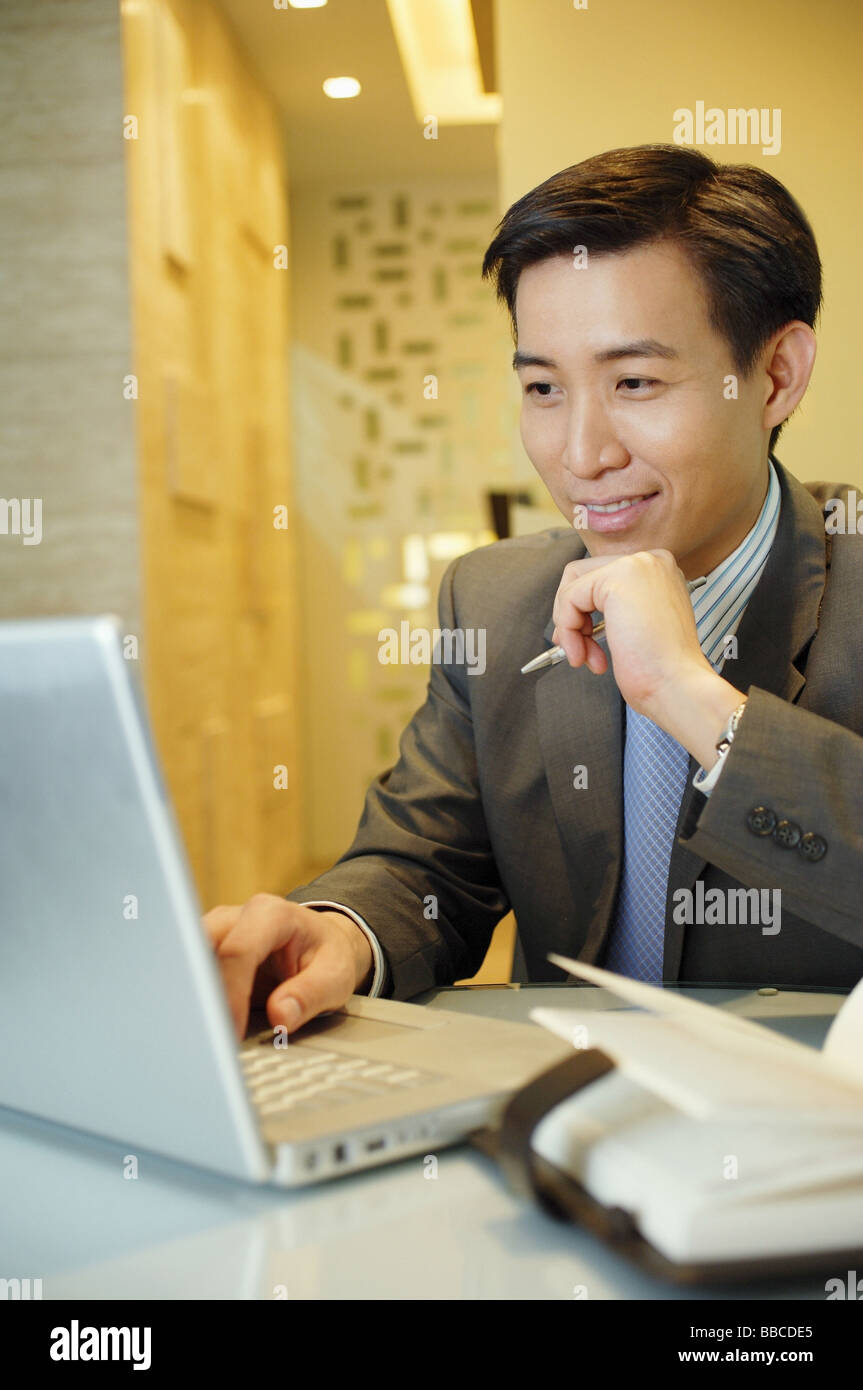 Businessman using laptop, hand on chin Stock Photo - Alamy