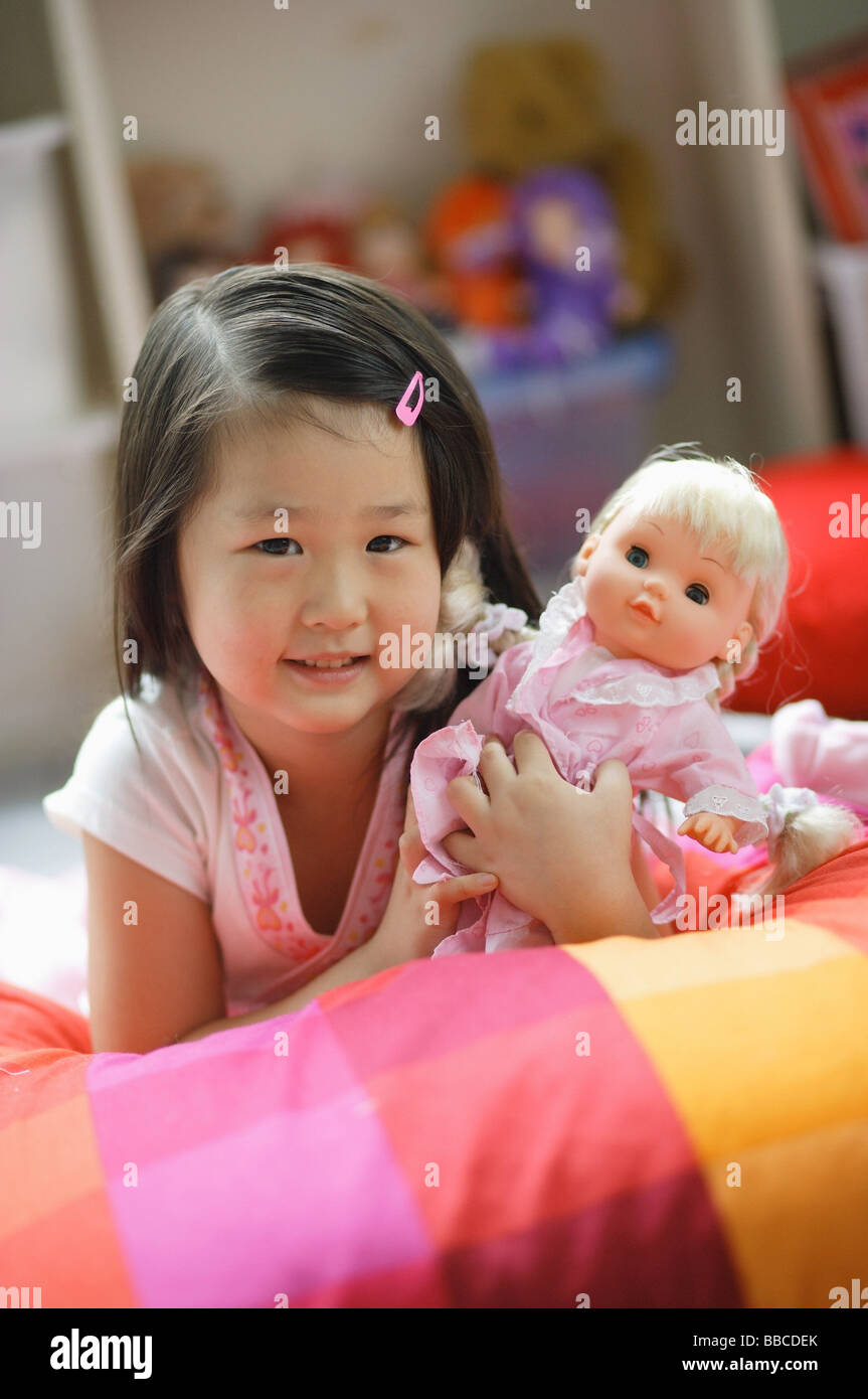 Girl lying on bed, holding a doll Stock Photo - Alamy