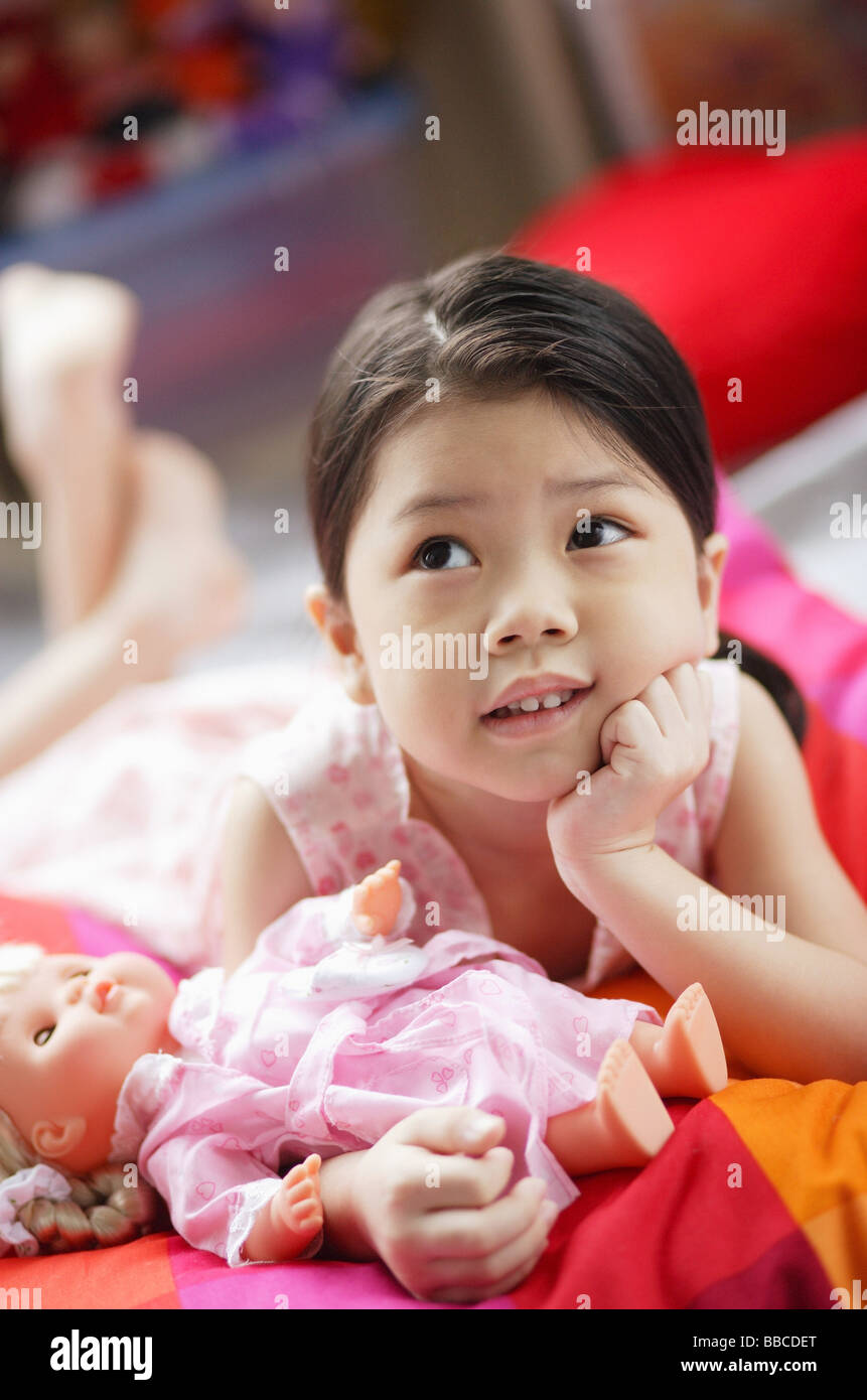 Girl holding a doll, looking up, hand on chin Stock Photo - Alamy