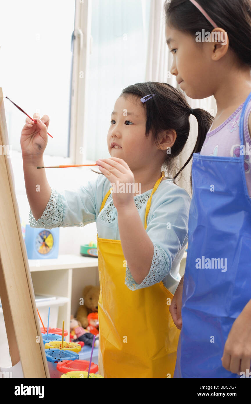 Two girls painting on easel Stock Photo - Alamy