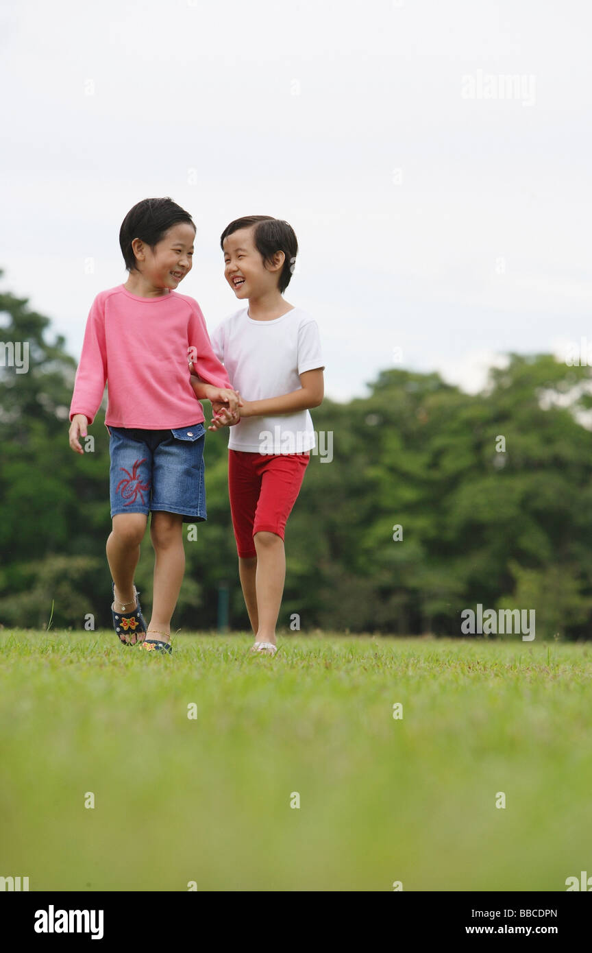 Two girls on grass, walking, side by side Stock Photo - Alamy