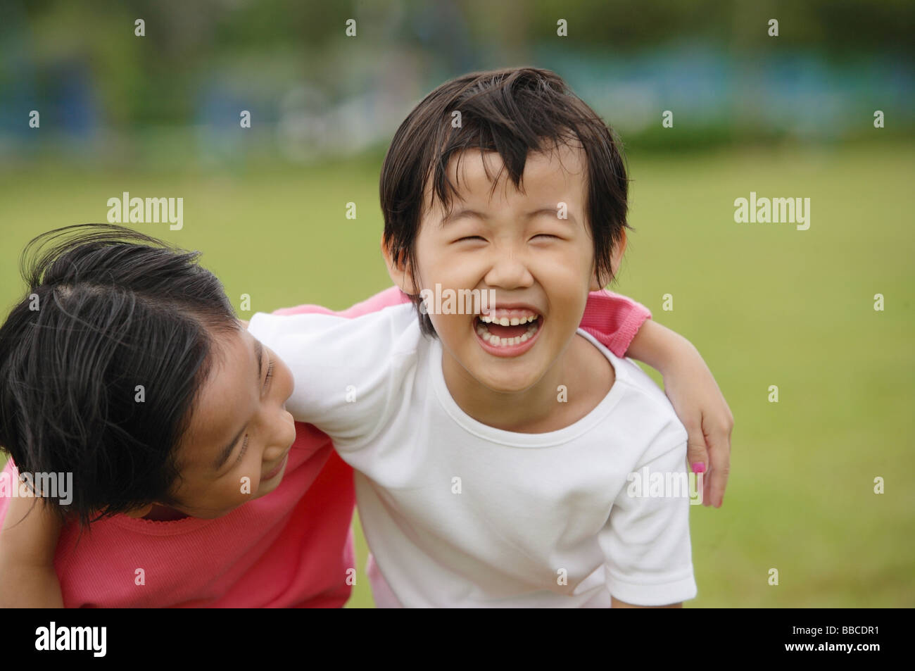 Two girls with arms around each other, laughing Stock Photo - Alamy